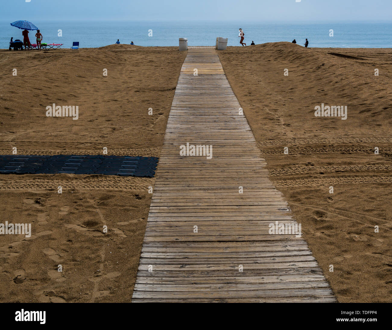 Photo of a wood path on the beach leading to the ocean; a jogger is ...