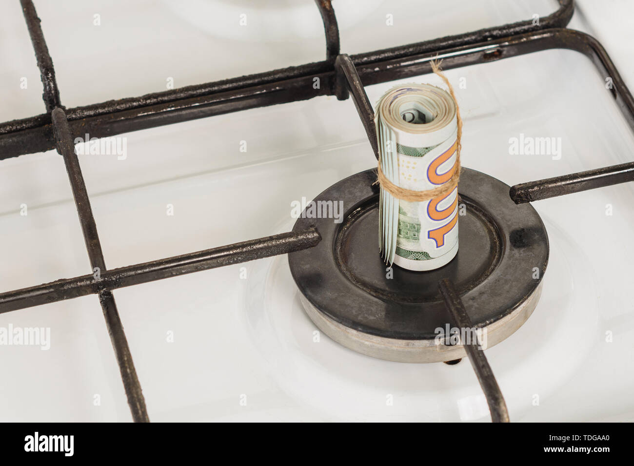 A stack of hundred-dollar bills on a gas stove in the center of gas ...