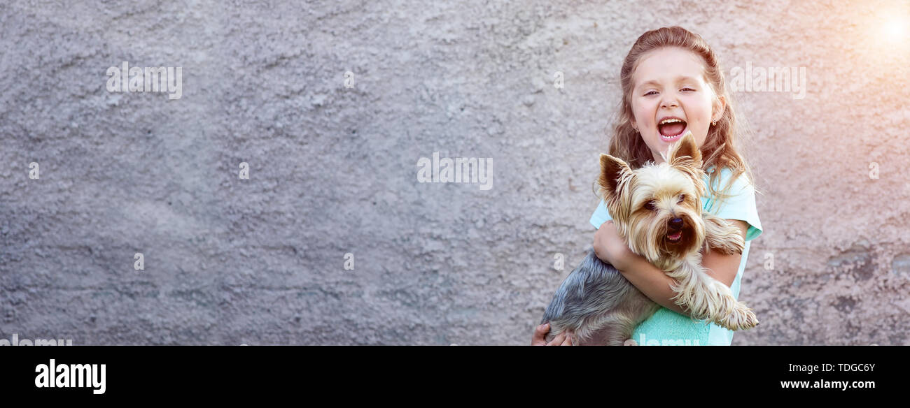 cute girl in a blue t-shirt with dimples on her cheeks holding a dog ...
