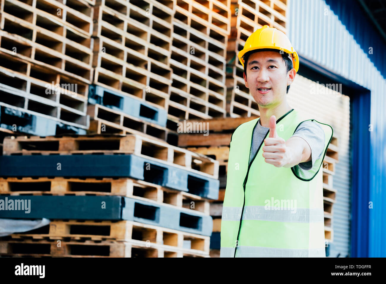 Smiling industrial logistics worker with safety helmet in warehouse ...