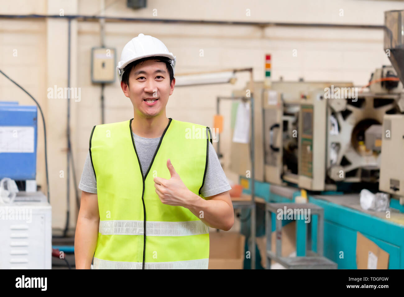 Asian factory worker with safety hat posed looking at camera with happy ...