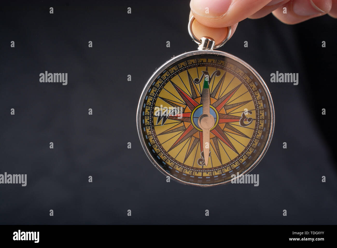 Hand is holding a magnetic compass on black background Stock Photo - Alamy