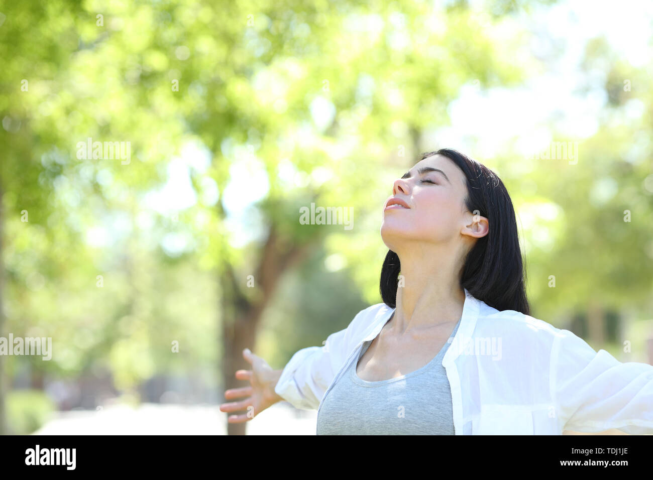 Woman relaxing in a park breathing deeply fresh air with a green ...