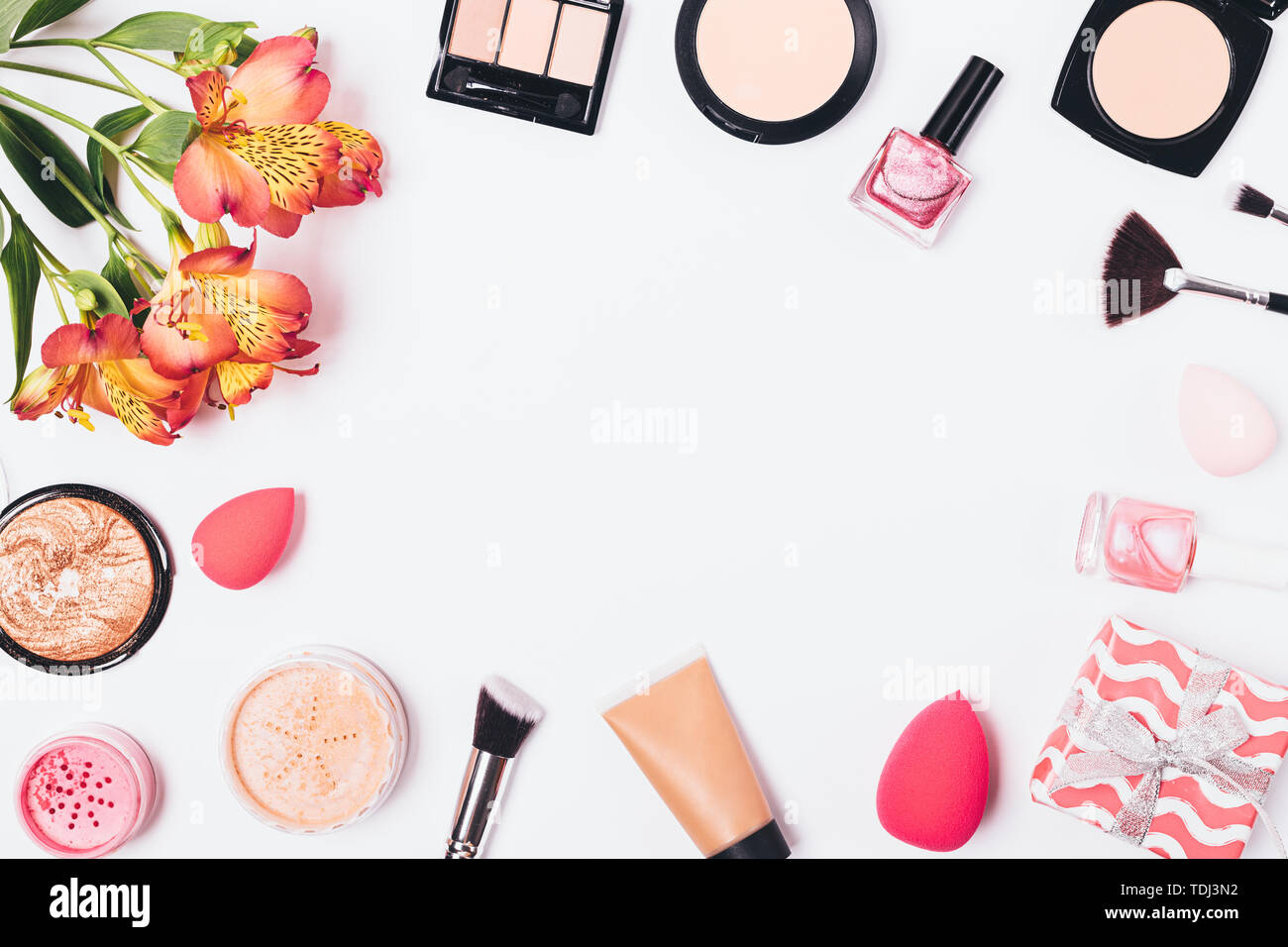 Makeup products near brushes and blending sponges, floral flat lay ...