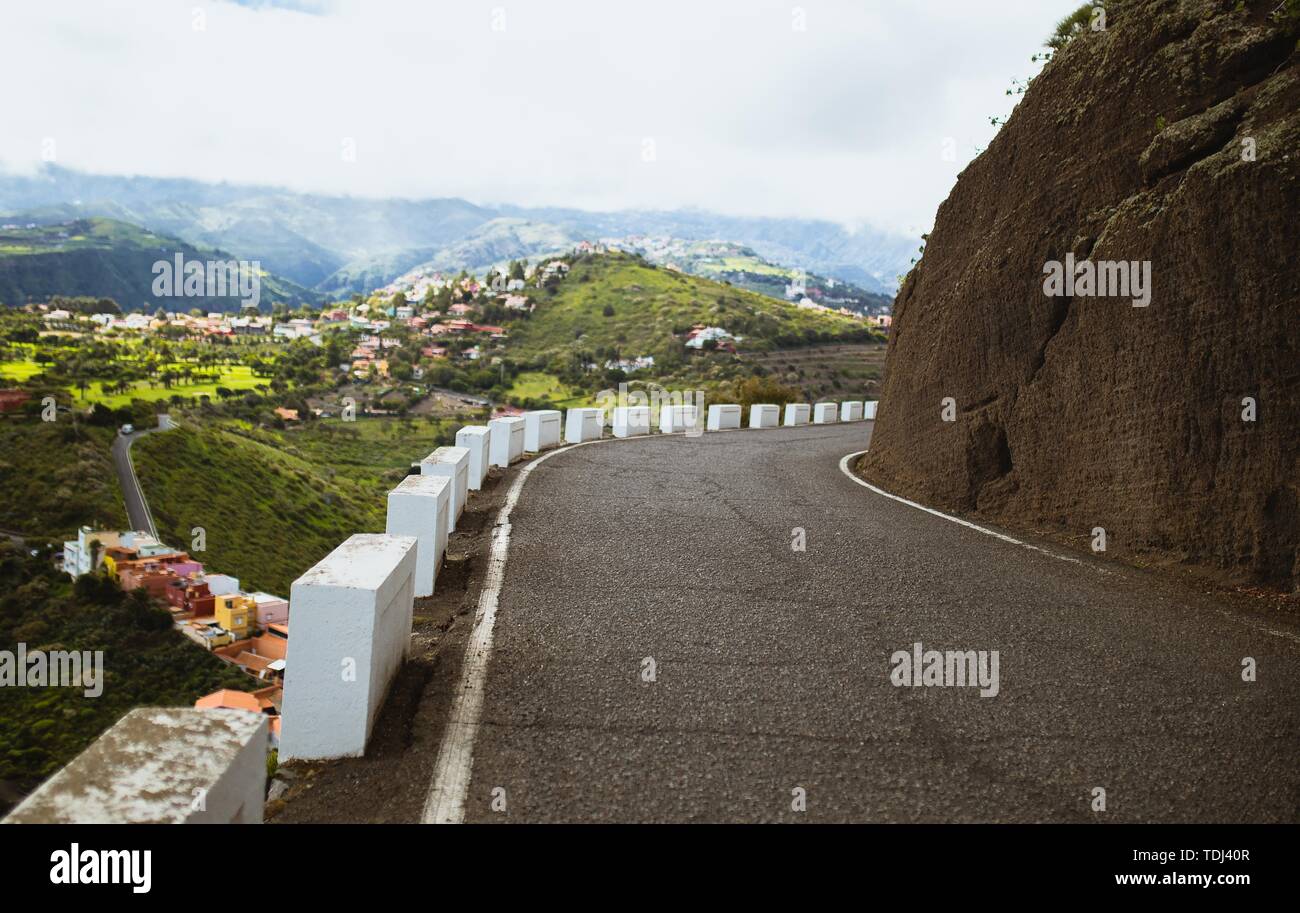 Road next a hill with white roadside pillars Stock Photo - Alamy