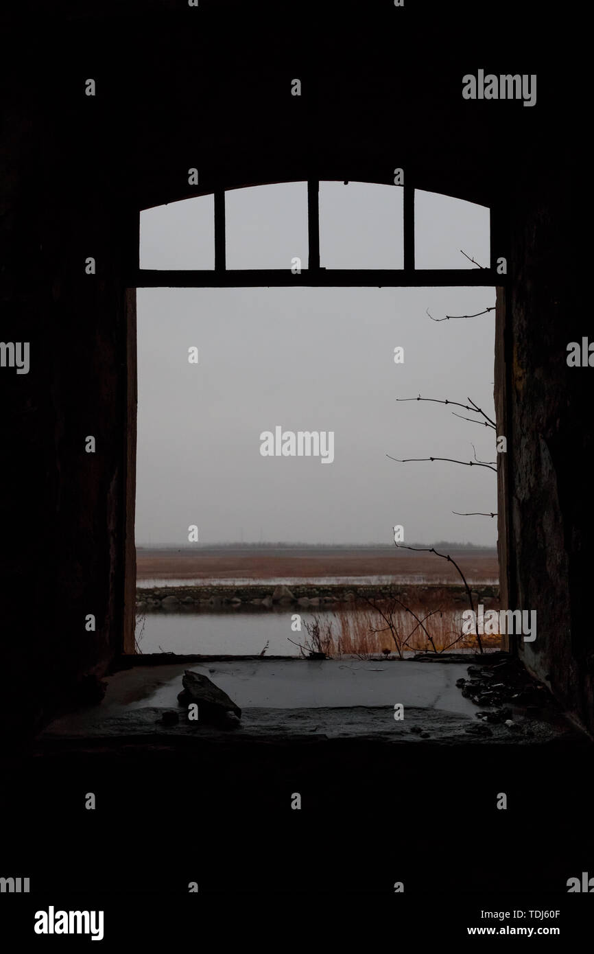 gloomy and broken window opening with a view of the sea in foggy time ...