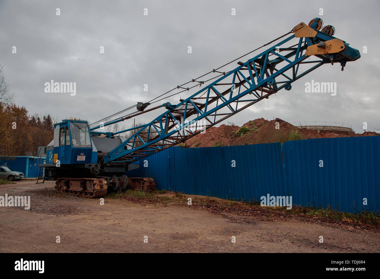 working crane parked near the blue fence Stock Photo - Alamy