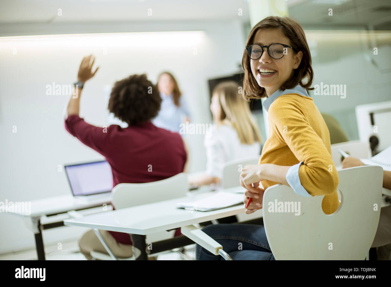 Young female student with eyeglasses looking back in the classroom ...