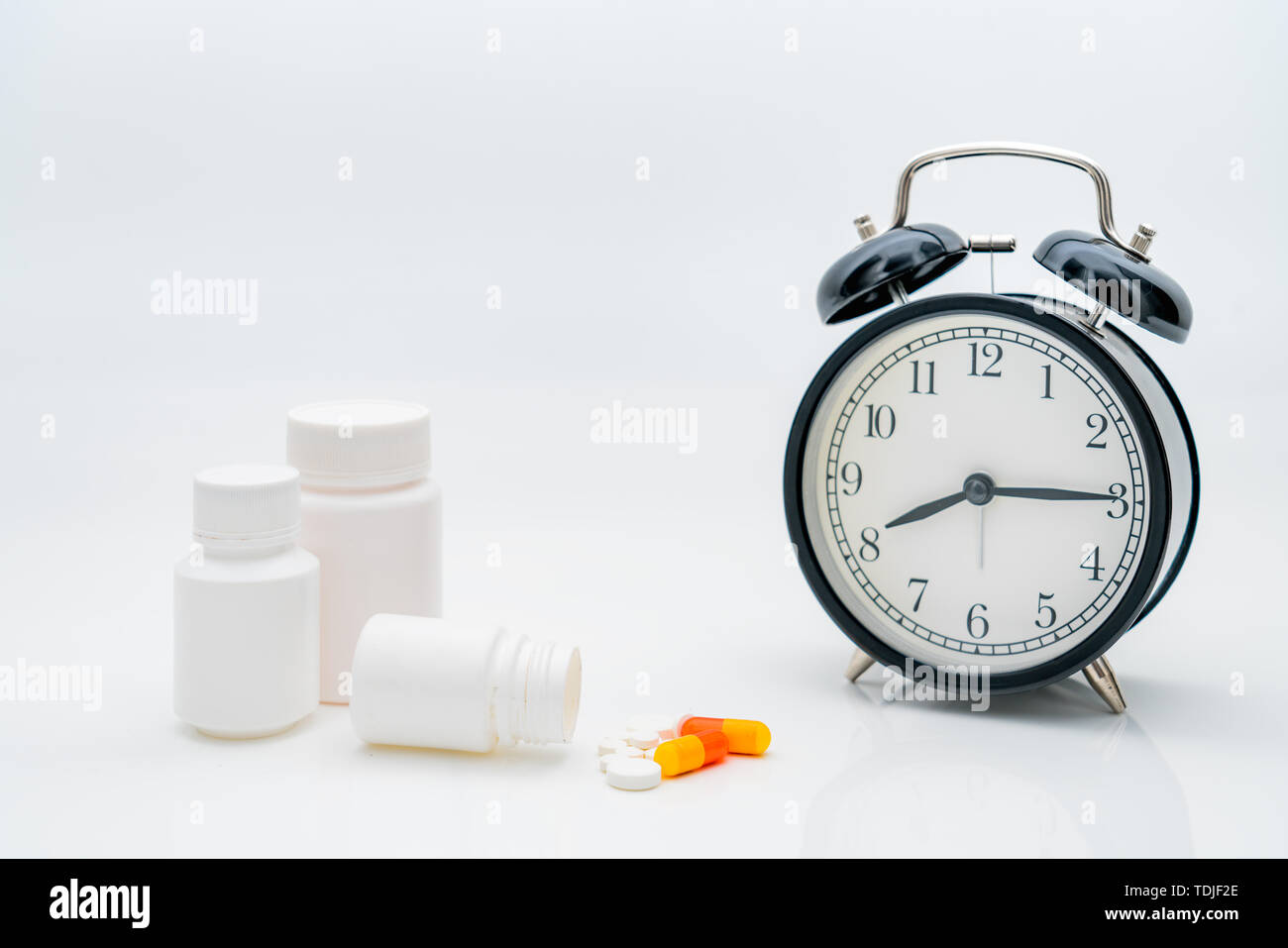 Tablets, capsules and alarm clocks on white background Stock Photo - Alamy