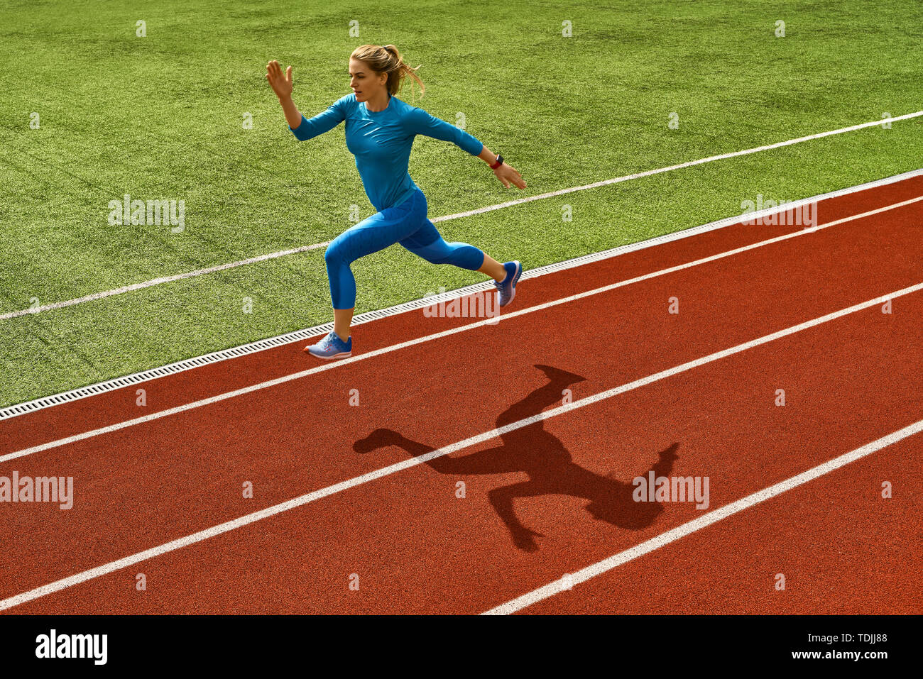 Amazing girl in a blue sportswear and sneakers starts her sprint run ...