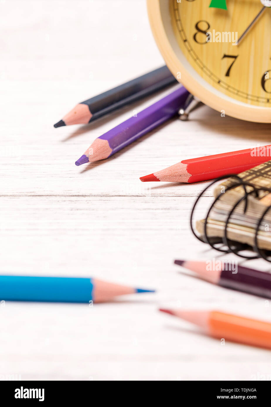Colorful pencil and notebook on table with alarm clock Stock Photo - Alamy