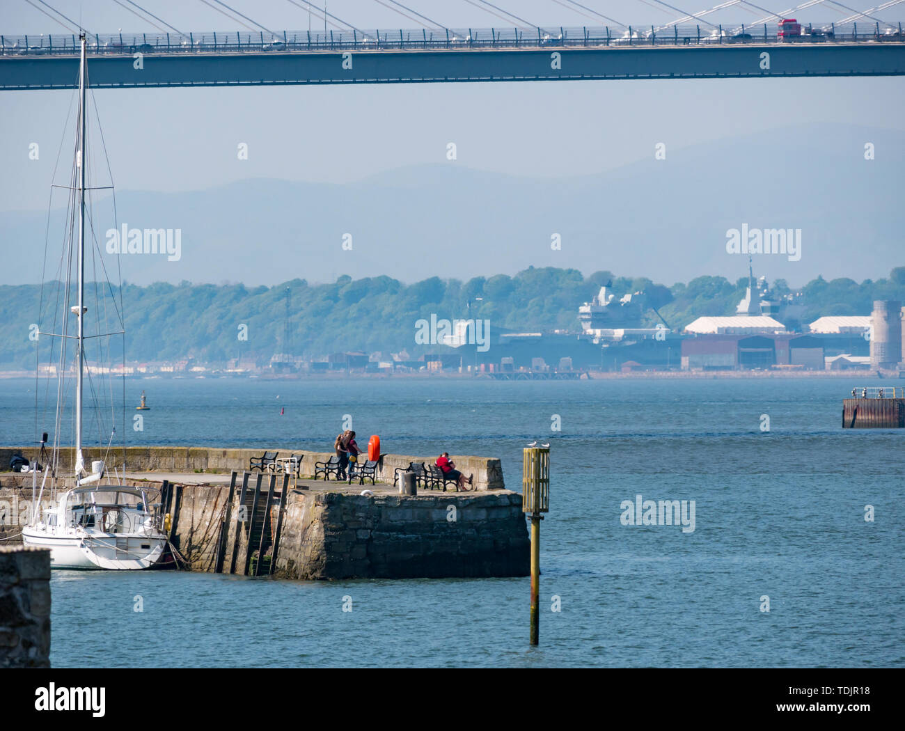 South Queensferry harbour with moored sailboat; HMS Queen Elizabeth ...