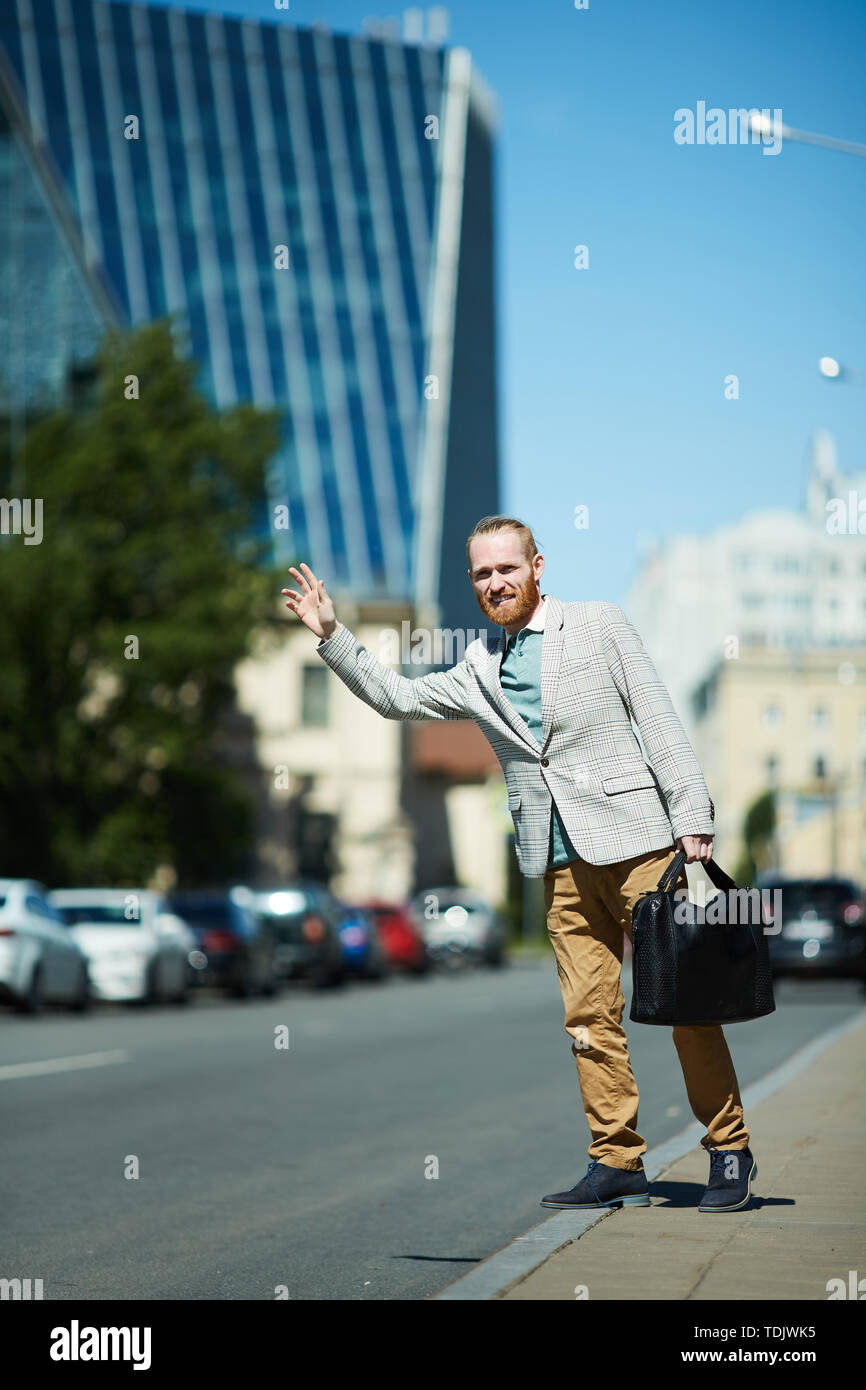 Positive handsome young businessman with briefcase waving hand while ... Positive handsome young businessman with briefcase waving hand while ...