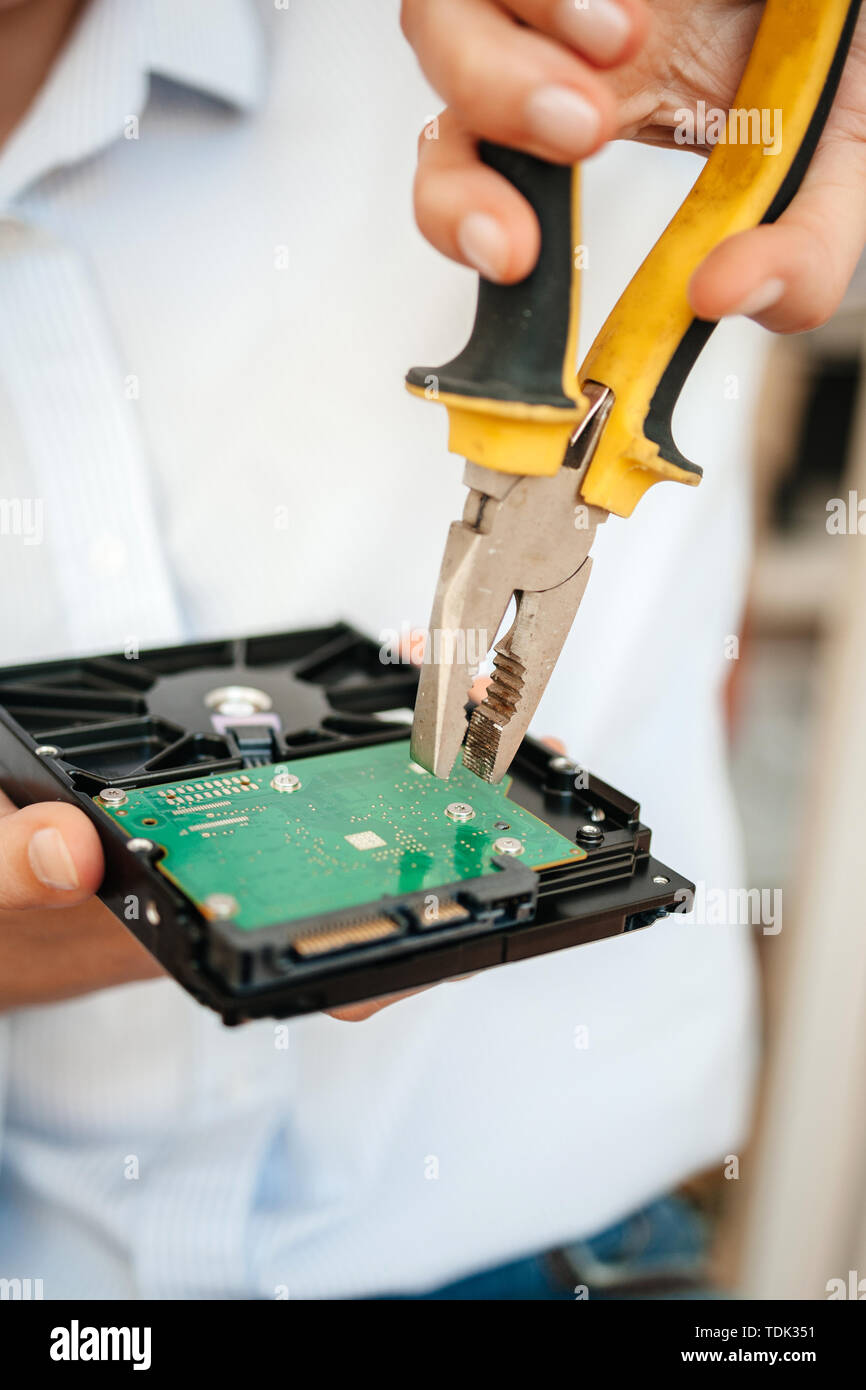 Female IT computer repair IT woman using yellow metal pliers to fix ...