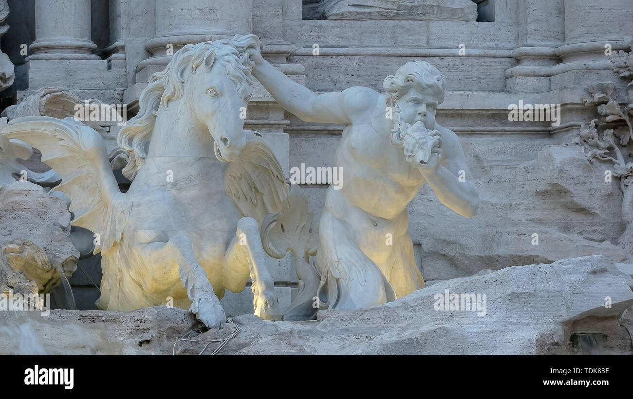 close up of the statue of triton at trevi fountain with lights on in ...