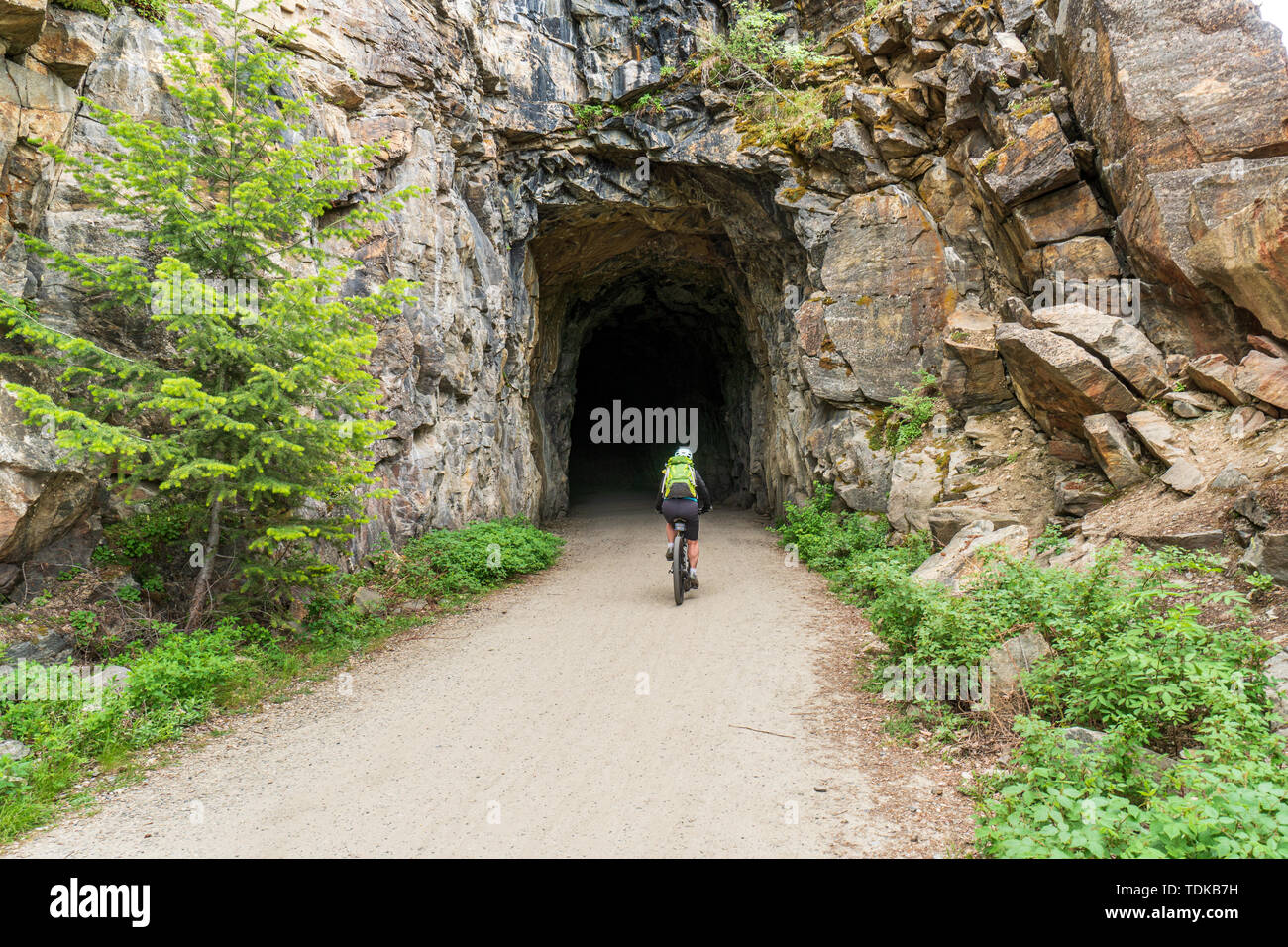 Woman bicycling at one of the tunnels of the Kettle Valley Railway (KVR ...