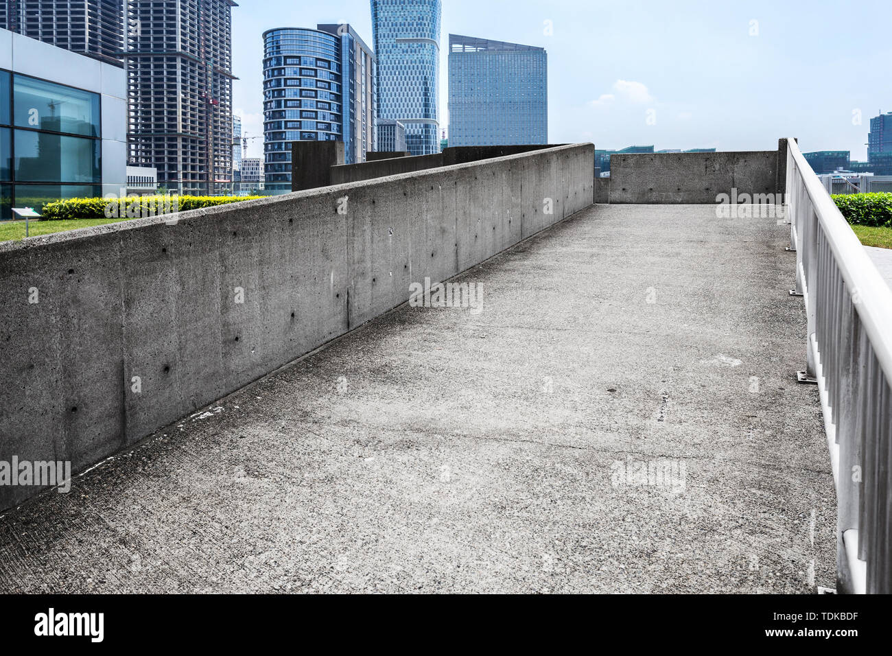 cityscape and empty concrete footpath by modern building in cloudy sky ...