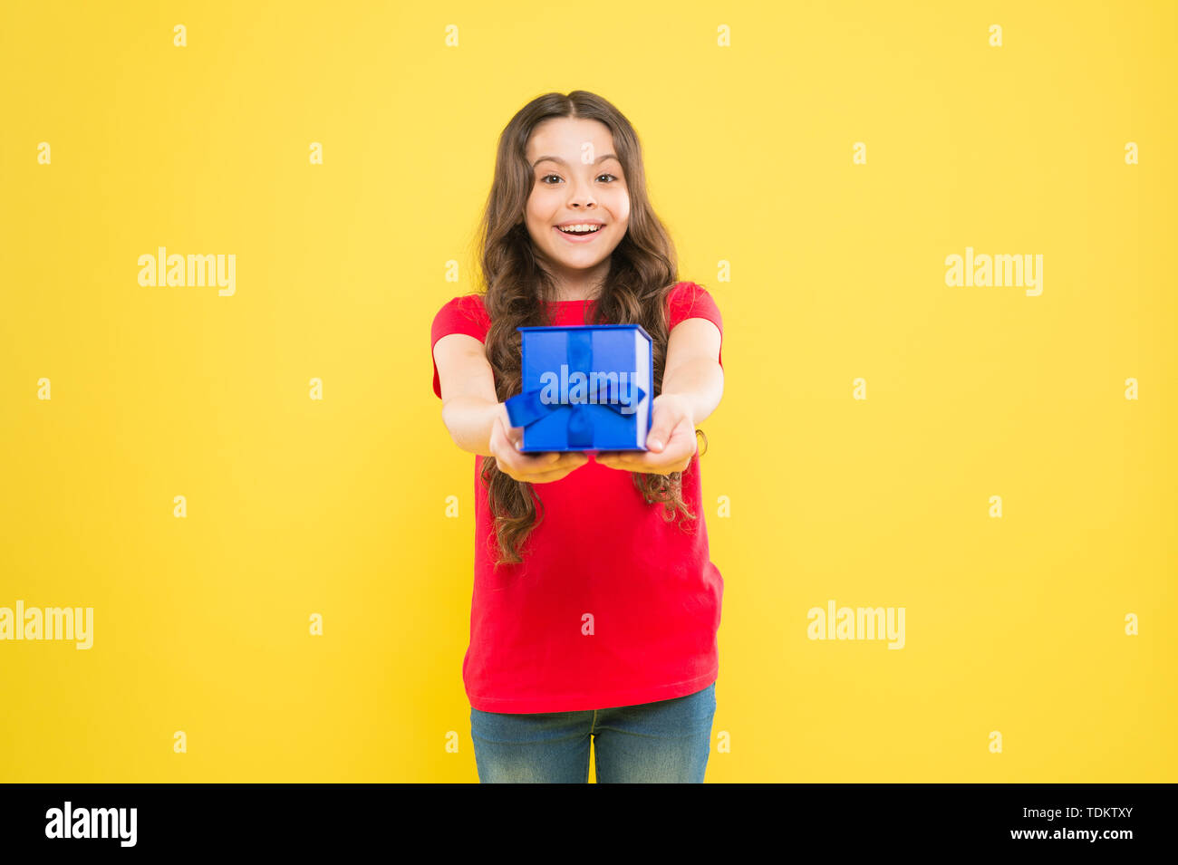 Gift giving makes her happy. Adorable little girl giving blue present ...
