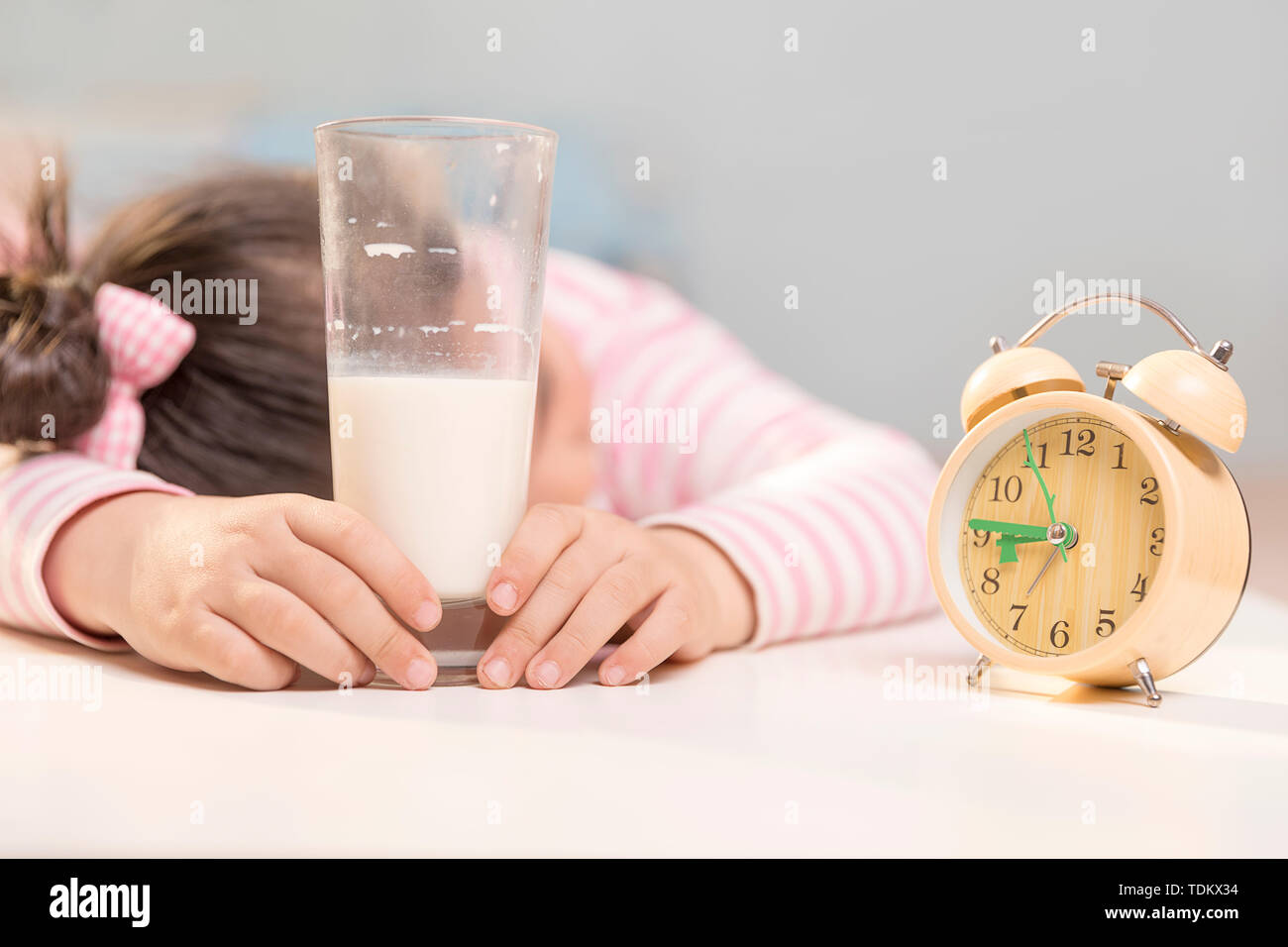 The little girl drinking milk and the alarm clock on the table Stock ...