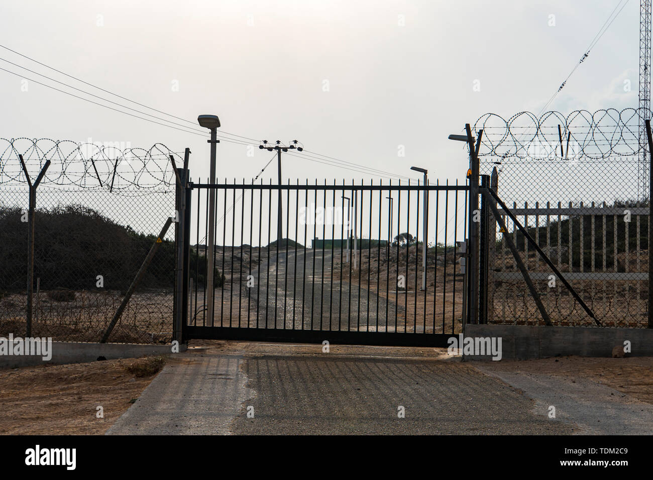 Barbed wire fence block the way. gate to a closed area. Automatic metal ...