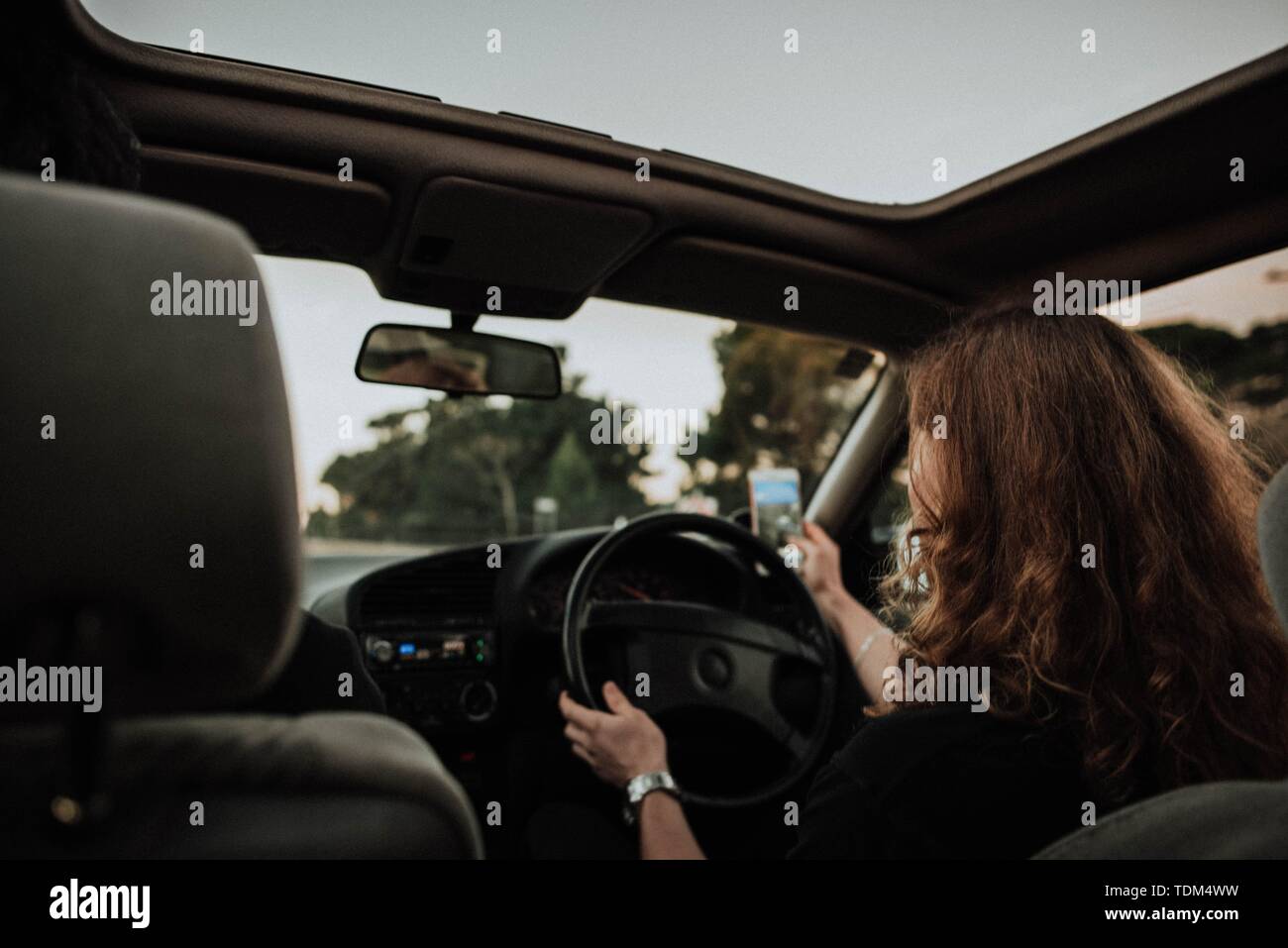 Female in front of a wheel of a car shot from the inside of the vehicle ...