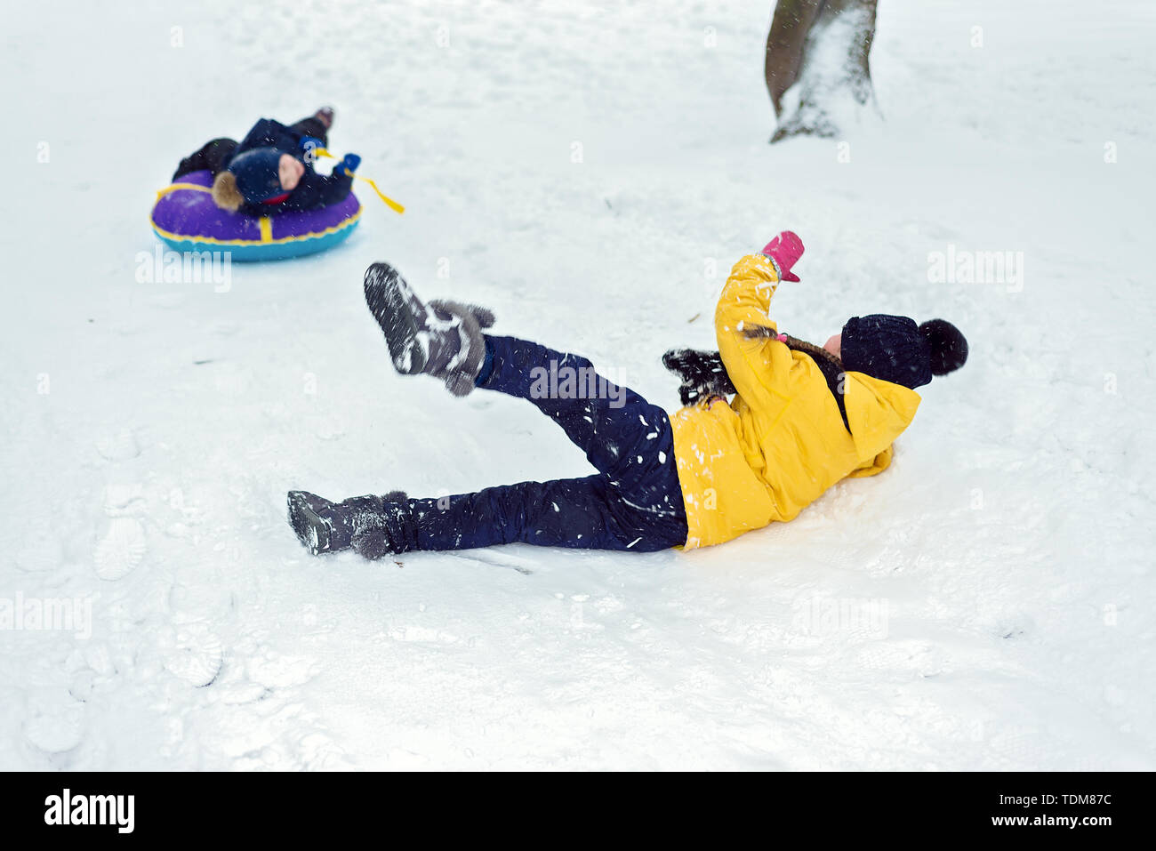 happy children ride a winter slide on a sled. brother and sister play ...