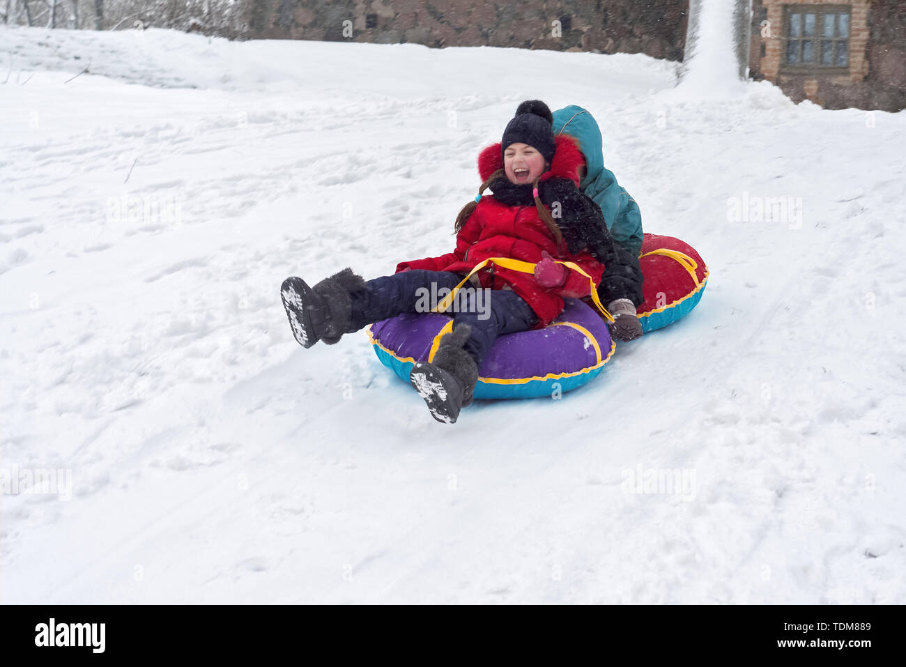 boy and girl sledding from the mountain. happy children. emotional ...