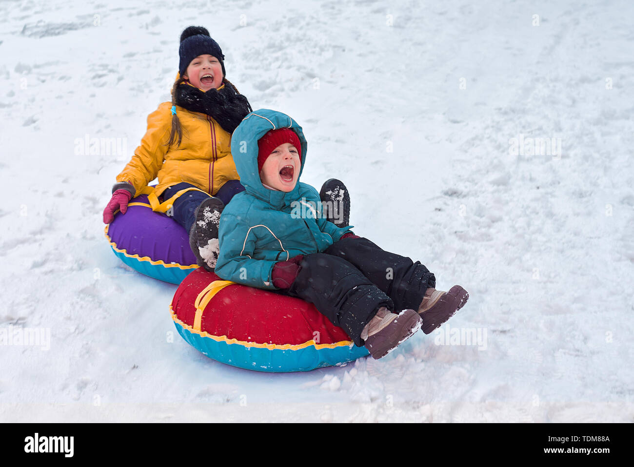 boy and girl sledding from the mountain. happy children. emotional ...