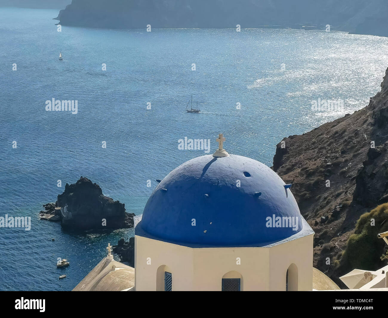 blue domed church with a yacht in the background at oia, santorini ...