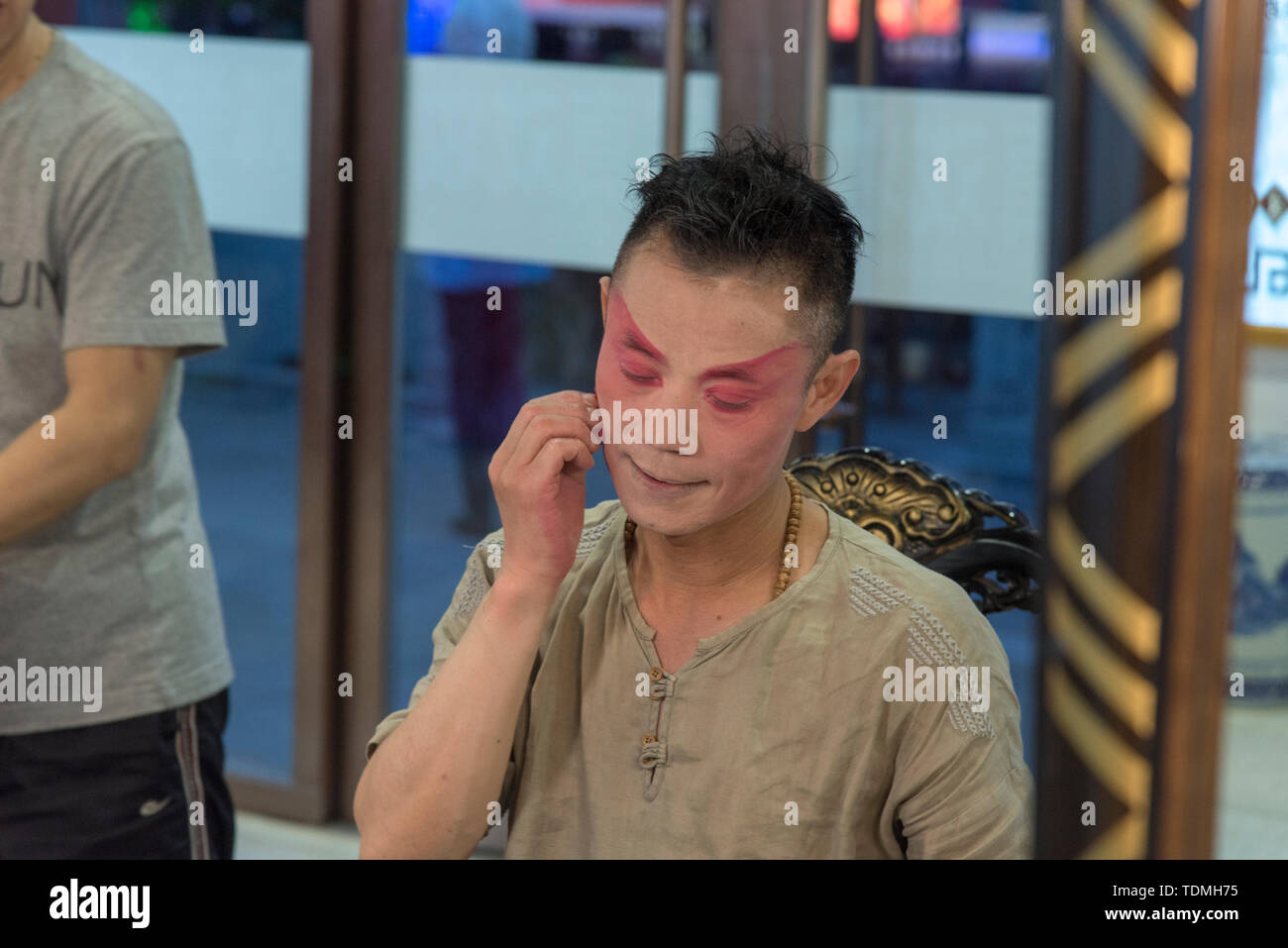 Traditional Chinese actor applies makeup before a performance in a ...