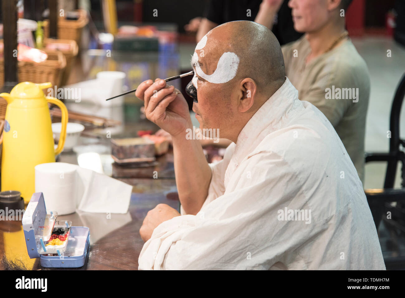 Traditional Chinese actor applies makeup before a performance in a ...