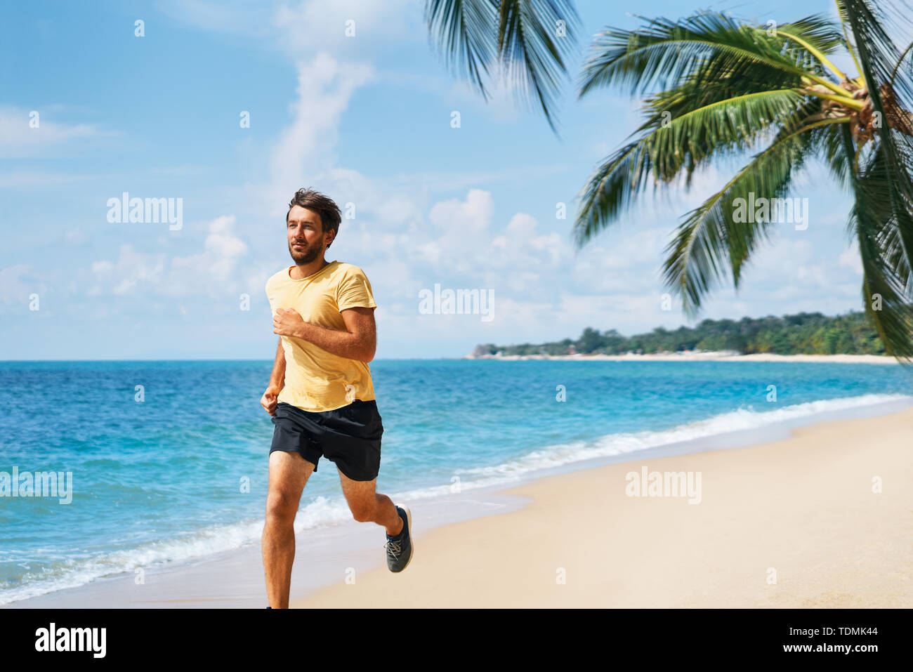 Young man running on the sea shore of tropical beach. Healthy lifestyle ...