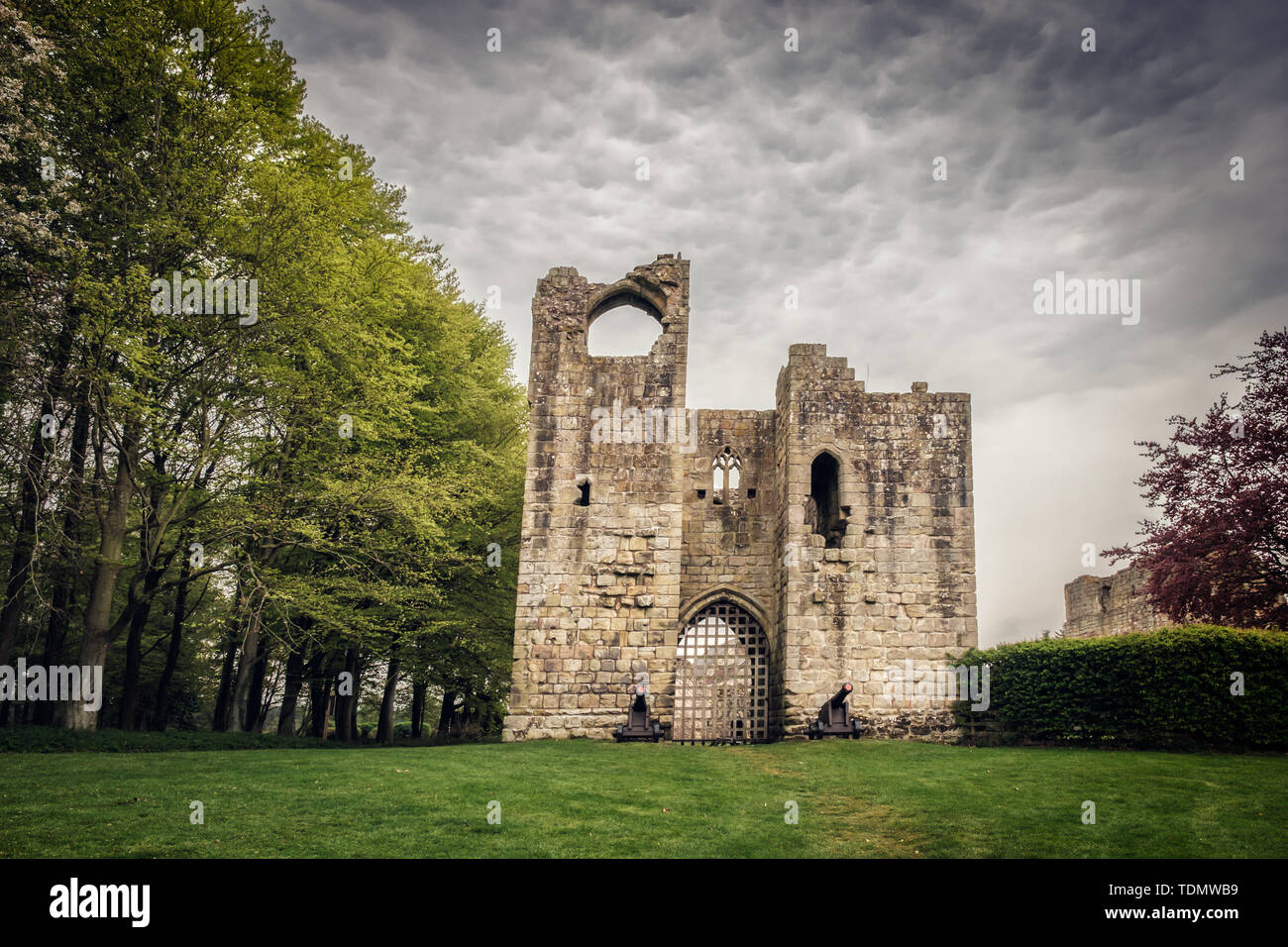 Dark storm clouds gather over the dramatic ruins of the medieval fortification of Etal Castle in ...
