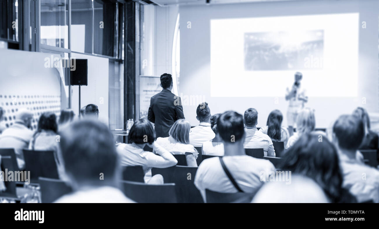 Businessman in audience standing and asking question to speeker at ...