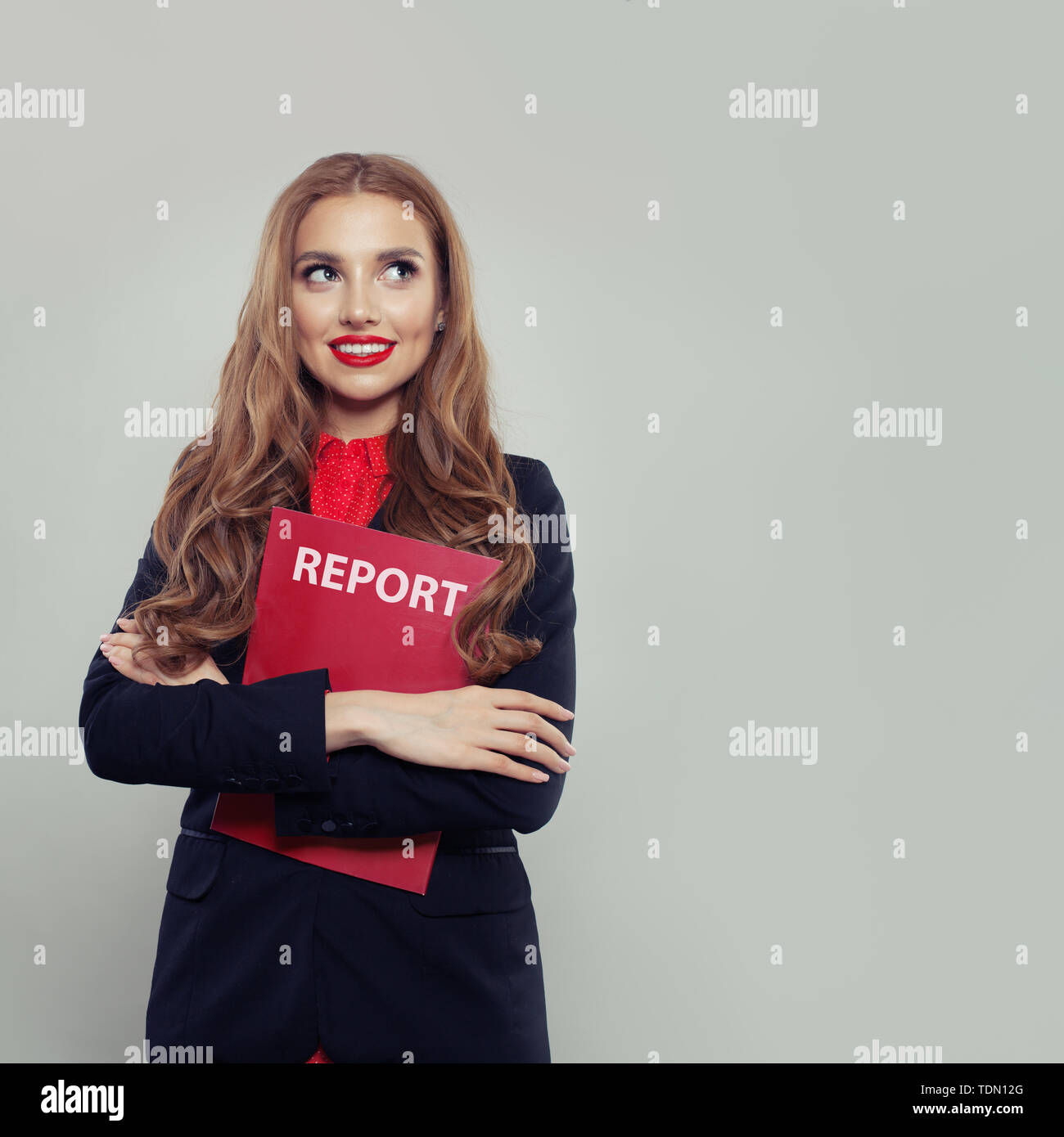 Happy business woman holding business report against white wall ...