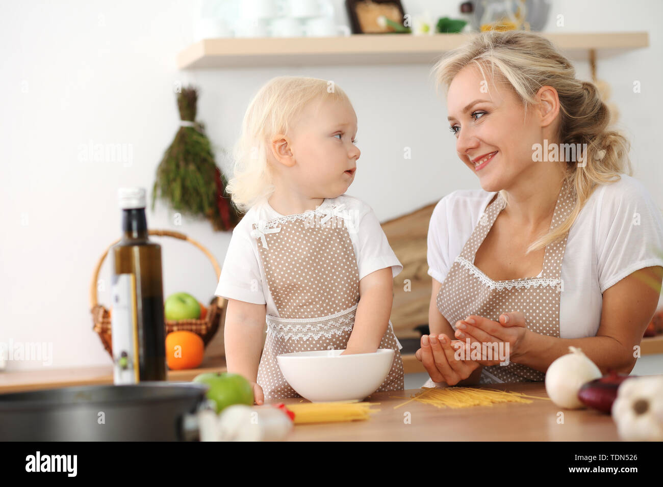 Happy mother and little daughter cooking in kitchen. Spending time all ...