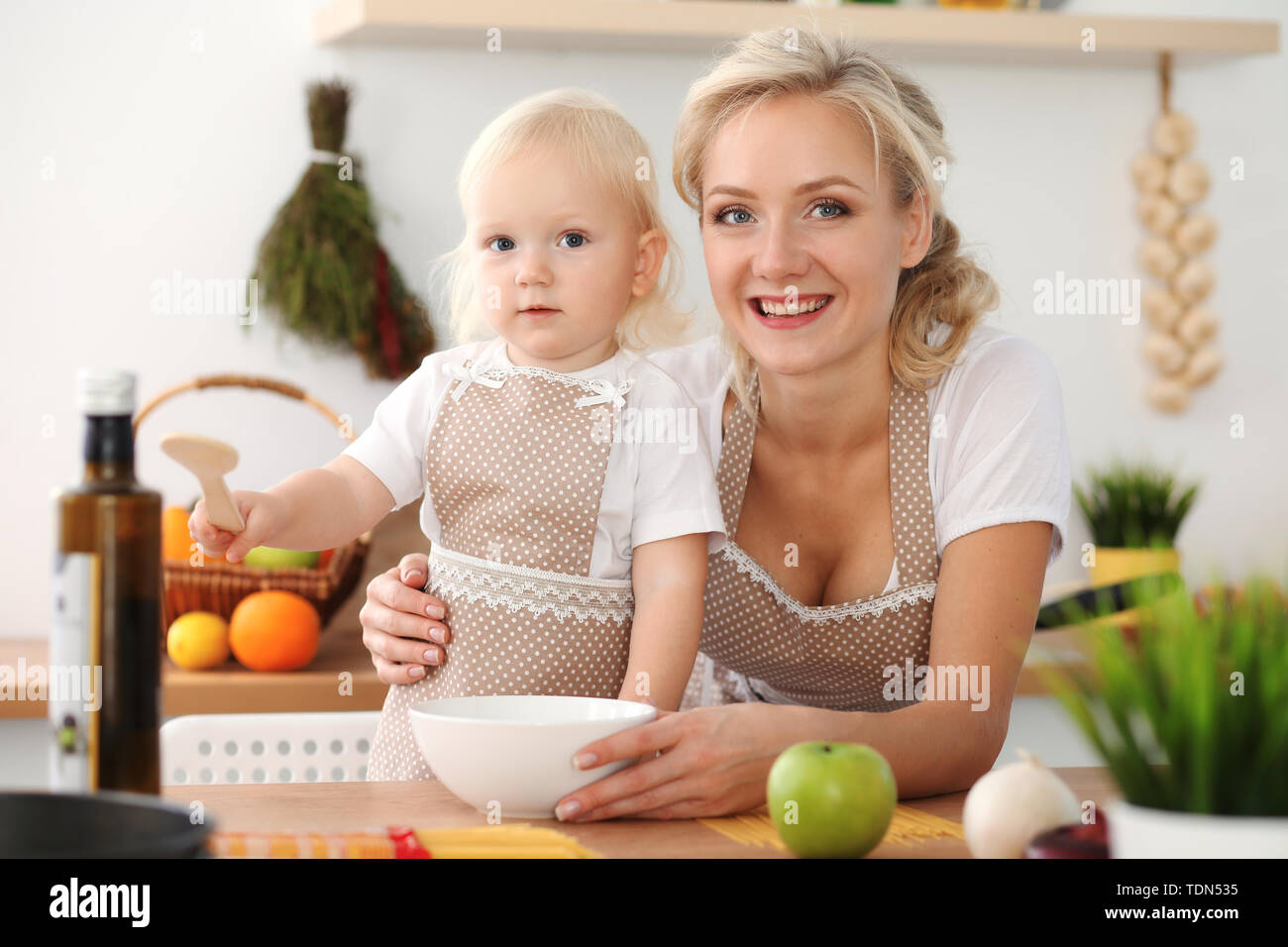 Happy mother and little daughter cooking in kitchen. Spending time all ...
