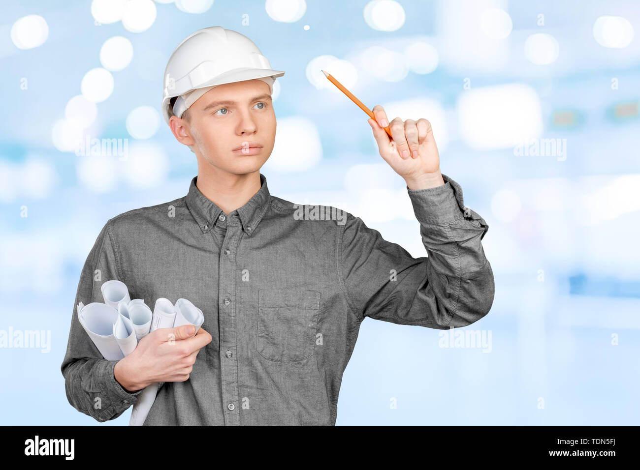 Young male engineer with helmet holding blueprints Stock Photo - Alamy