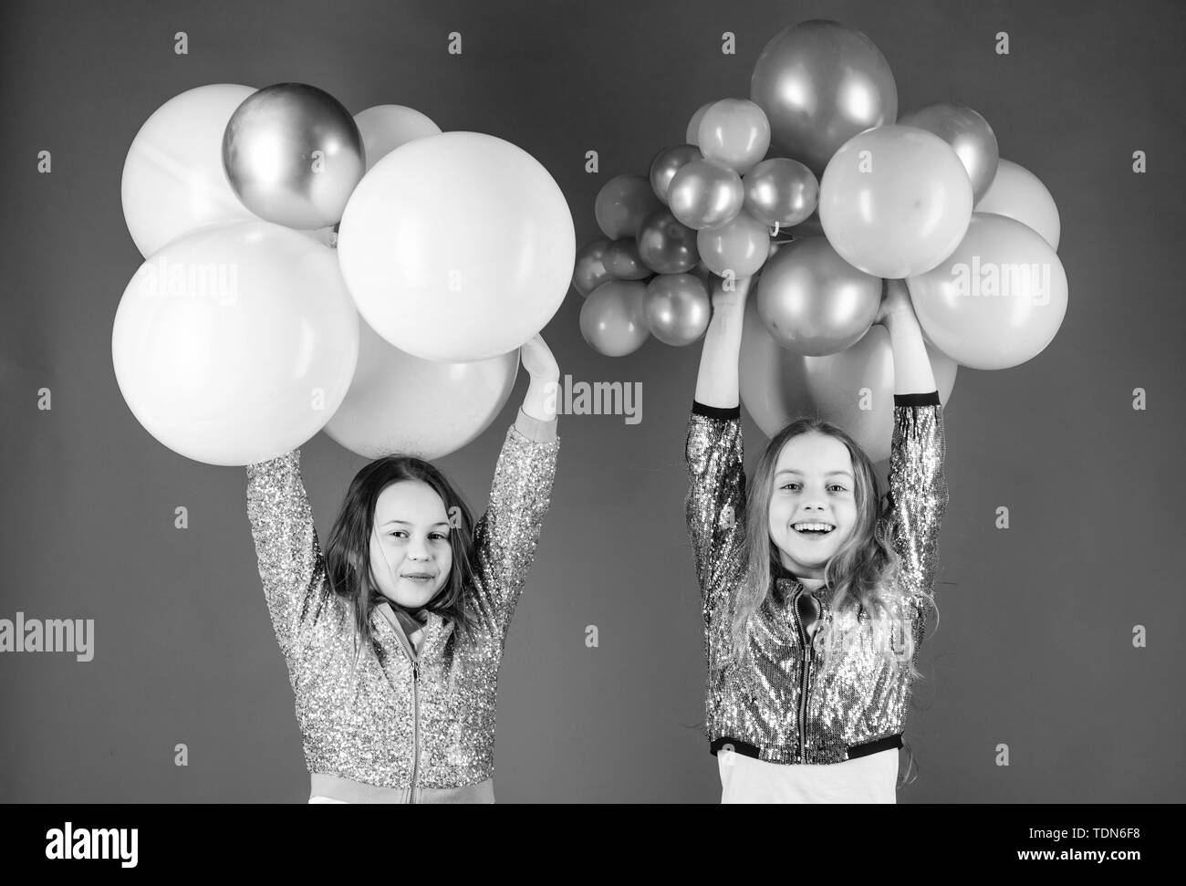 Creating happy moments. Little girls having fun with colorful balloons ...