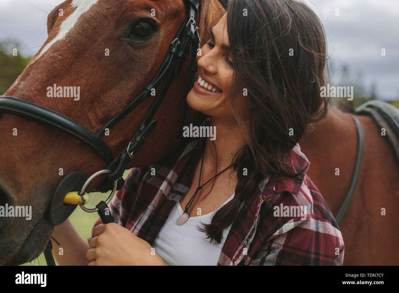 Close up of happy equestrian woman with a brown horse. Smiling cowgirl ...