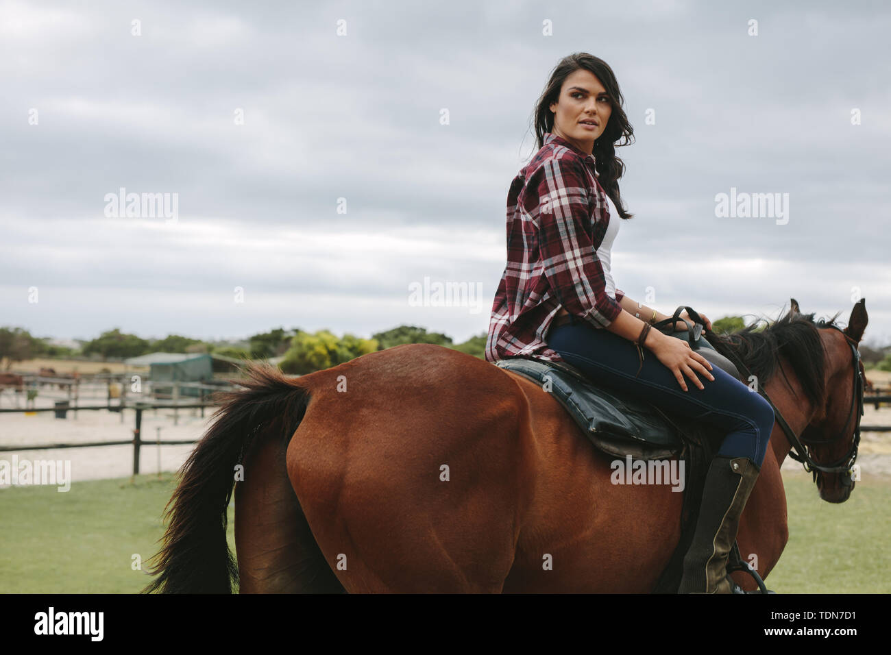 Beautiful young woman riding horse inside corral ranch. Equestrian ...