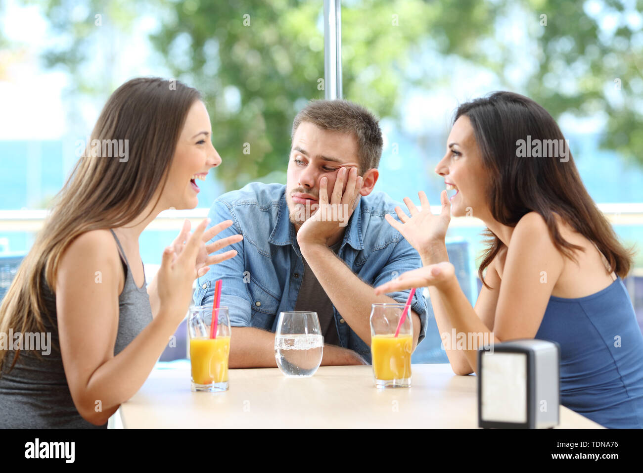 Bored man listening his friends conversation in a coffee shop or hotel ...