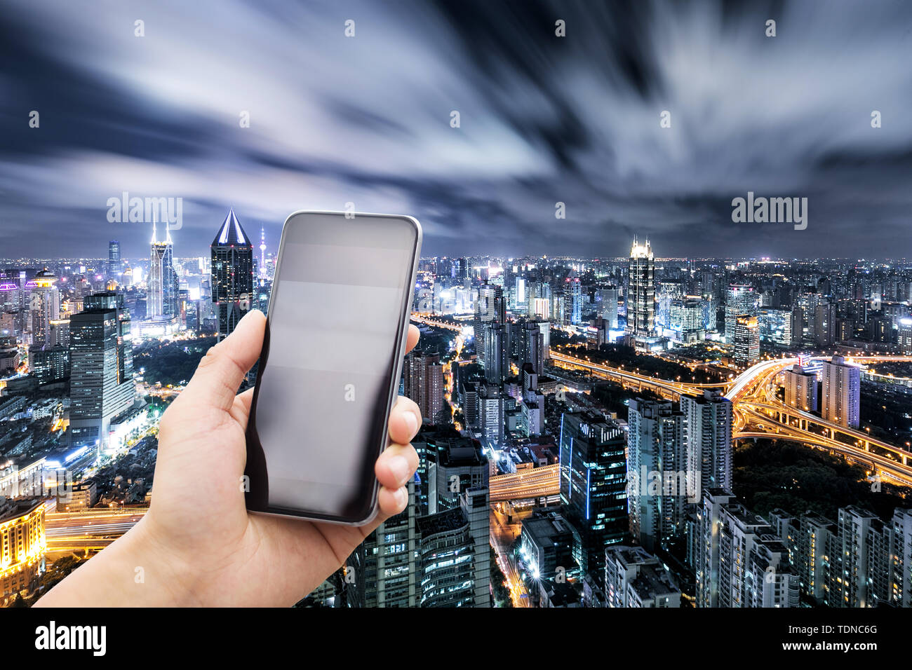 Mobile phone with modern city at night Stock Photo - Alamy