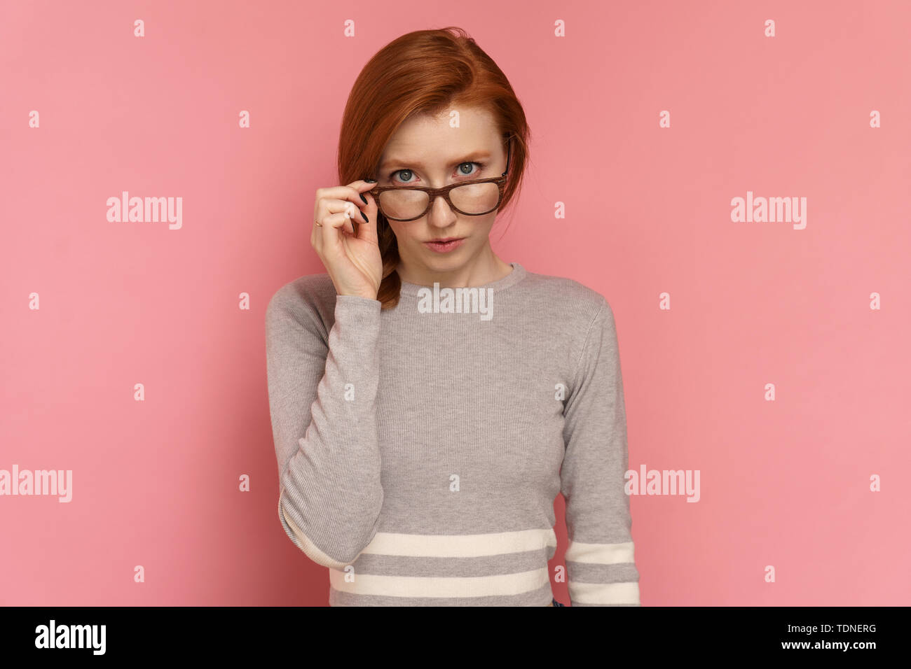 Red-haired girl looks intently and striclty at the camera through the ...