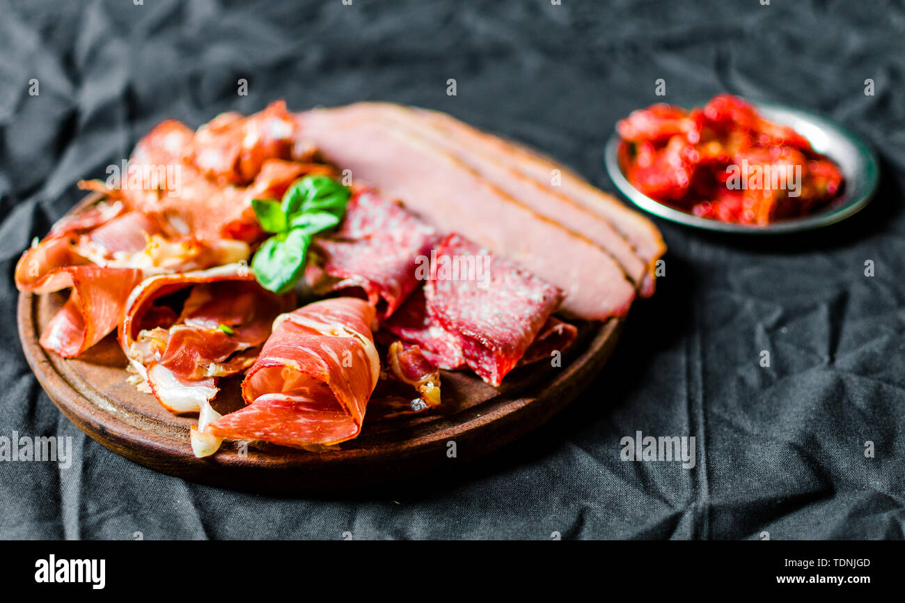 Italian cold meat antipasti delicatessen platter against black ...