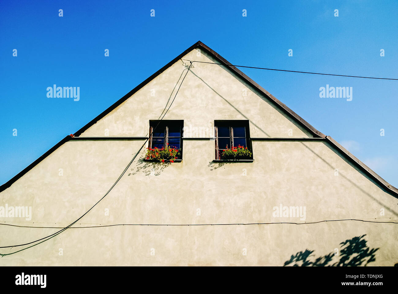 Triangular facade of a rural house with two square symmetrical windows ...