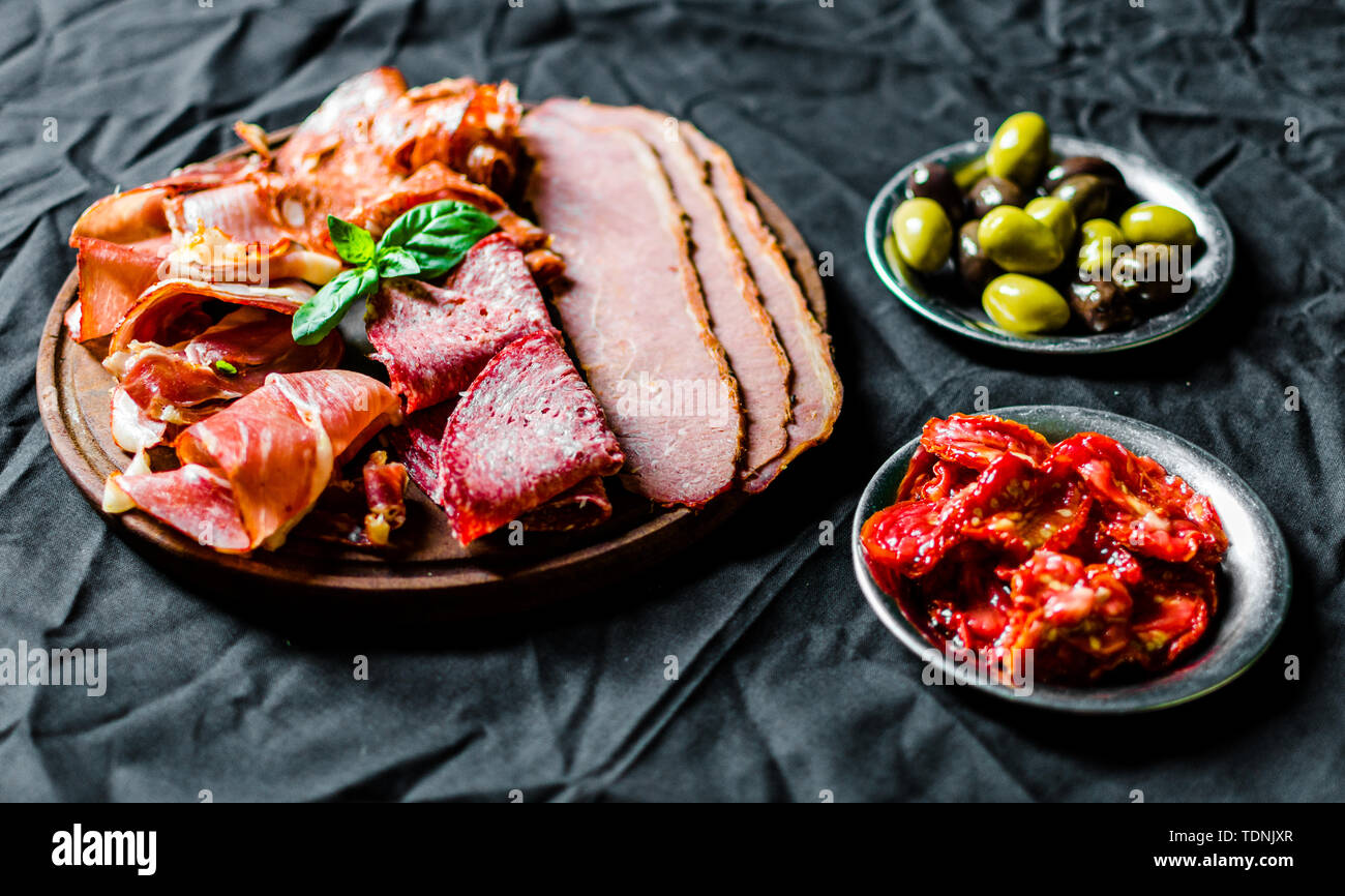Italian cold meat antipasti delicatessen platter against black ...