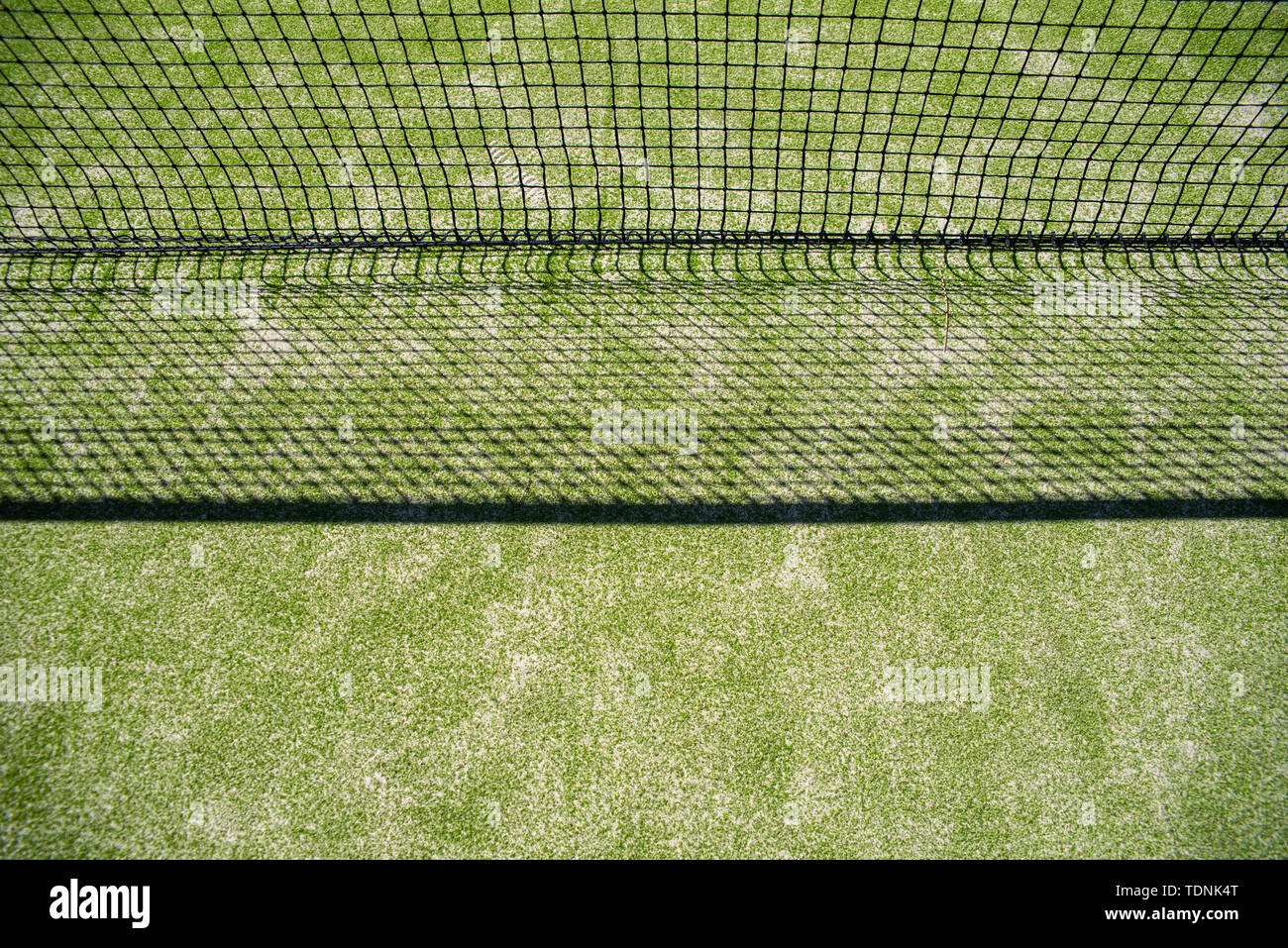 Net of a tennis court projecting its shadow on the grass, background ...