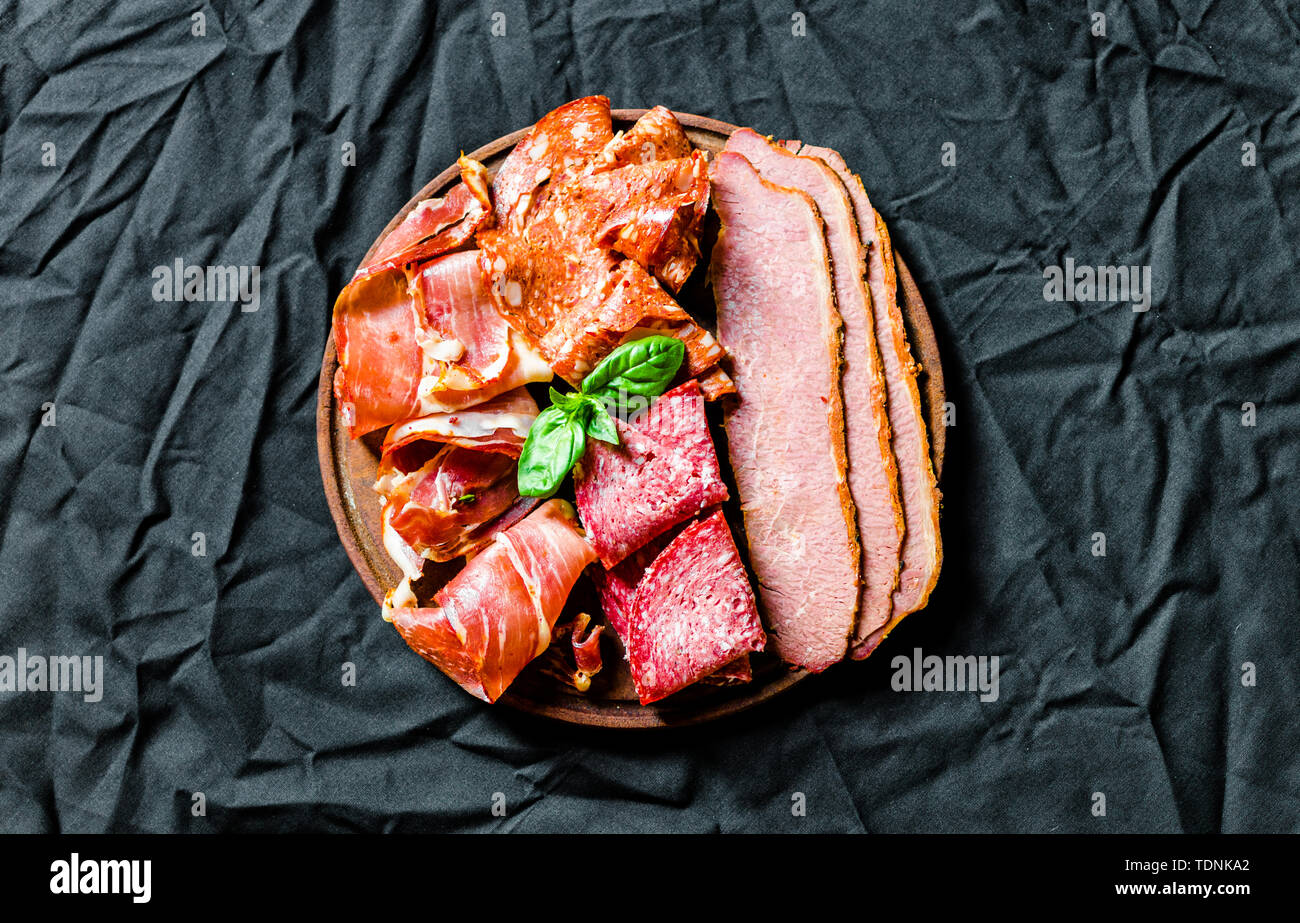 Italian cold meat antipasti delicatessen platter against black ...