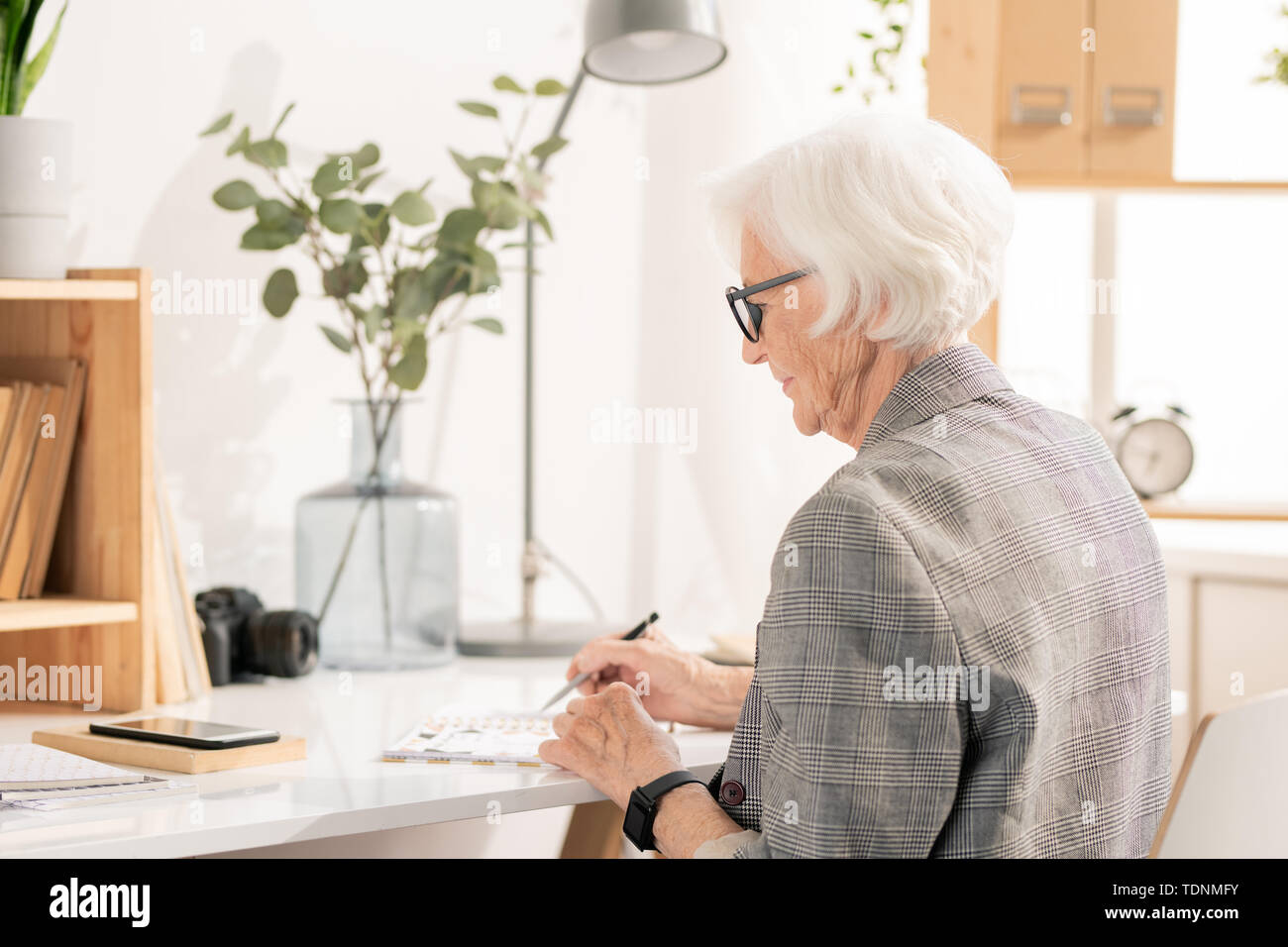 Elegant aged female office worker bending over open notebook on desk ...
